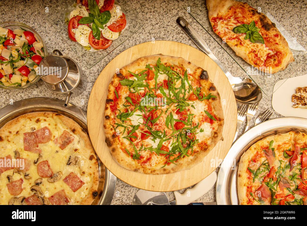 Pizzas and typical Italian dishes on a granite table. Margherita pizza ...