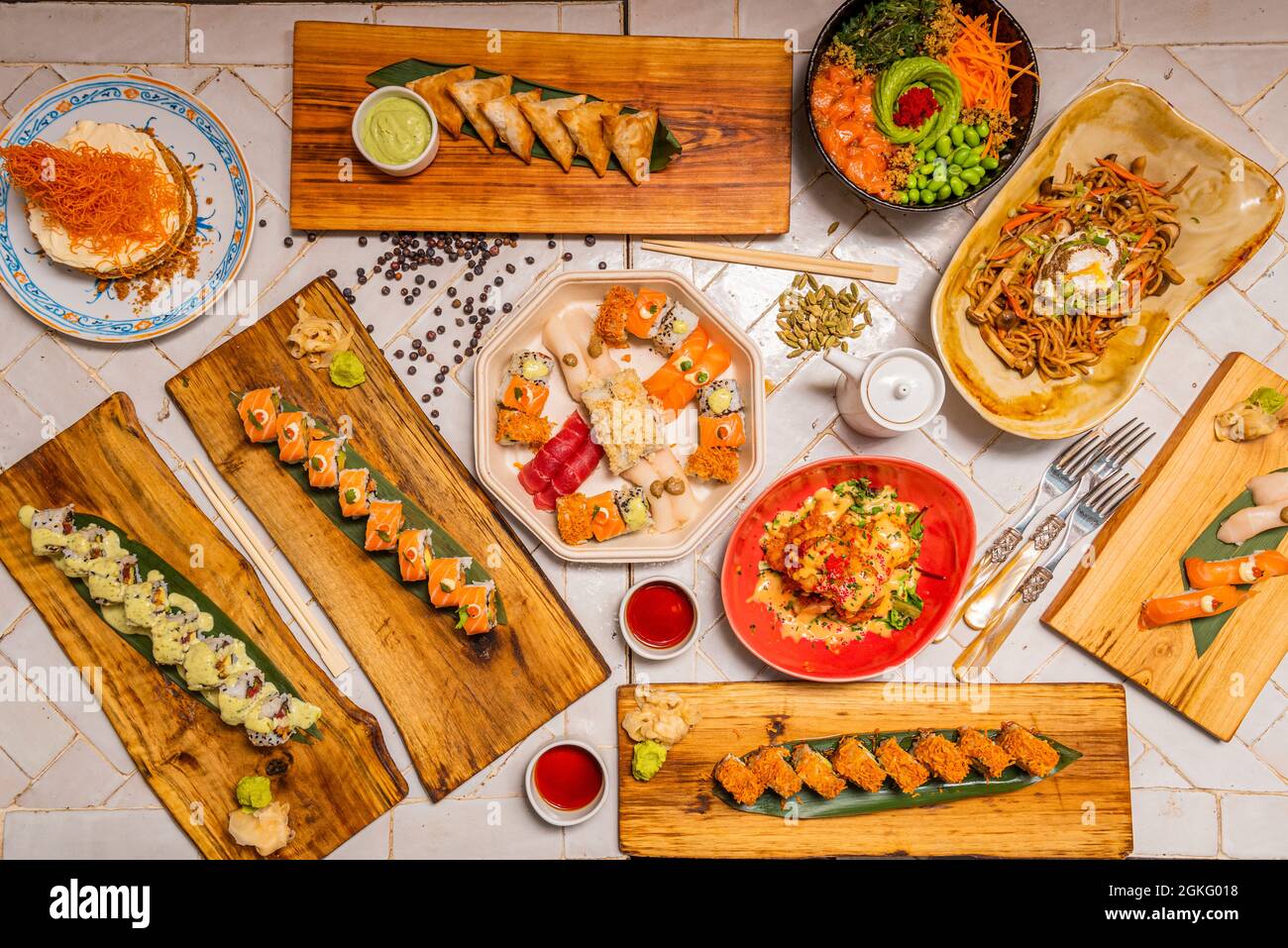 Assorted plates of Asian food and sushi on a white stoneware table ...