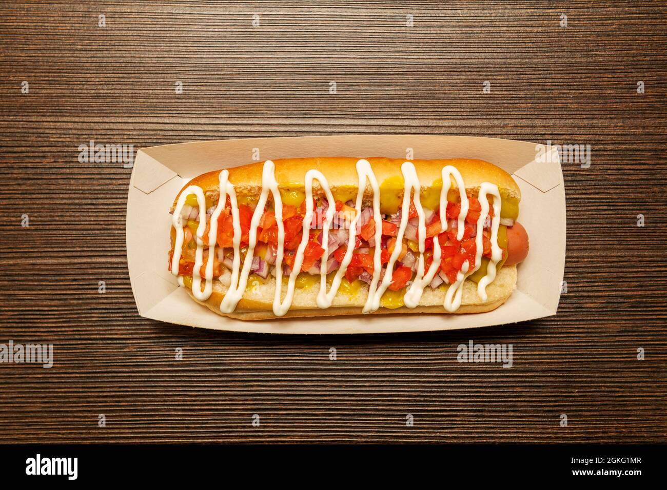 Hot dog in cardboard container with toppings with mayonnaise and ...