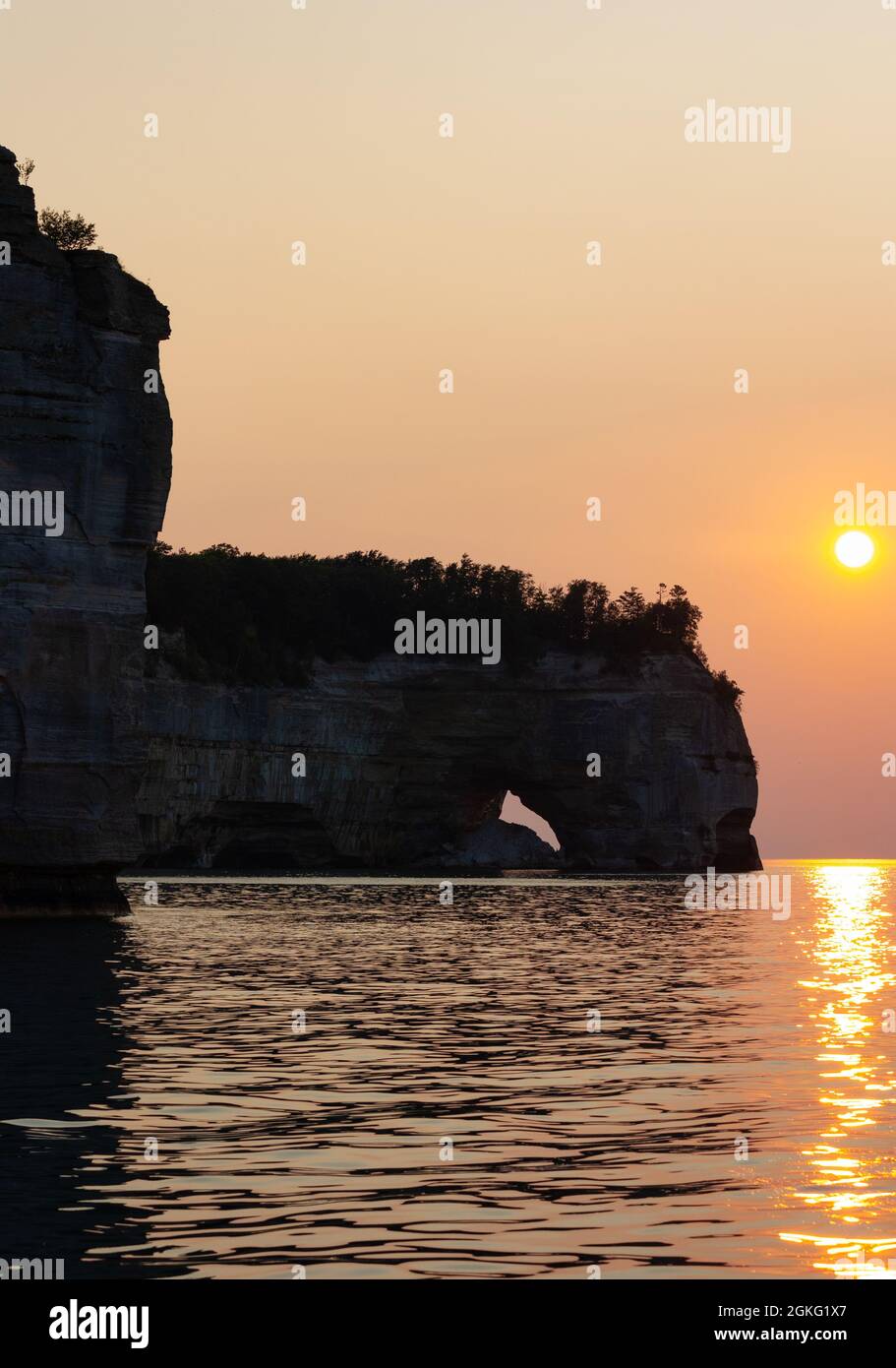 Sunset over a natural arch along Pictured Rocks National Lakeshore ...