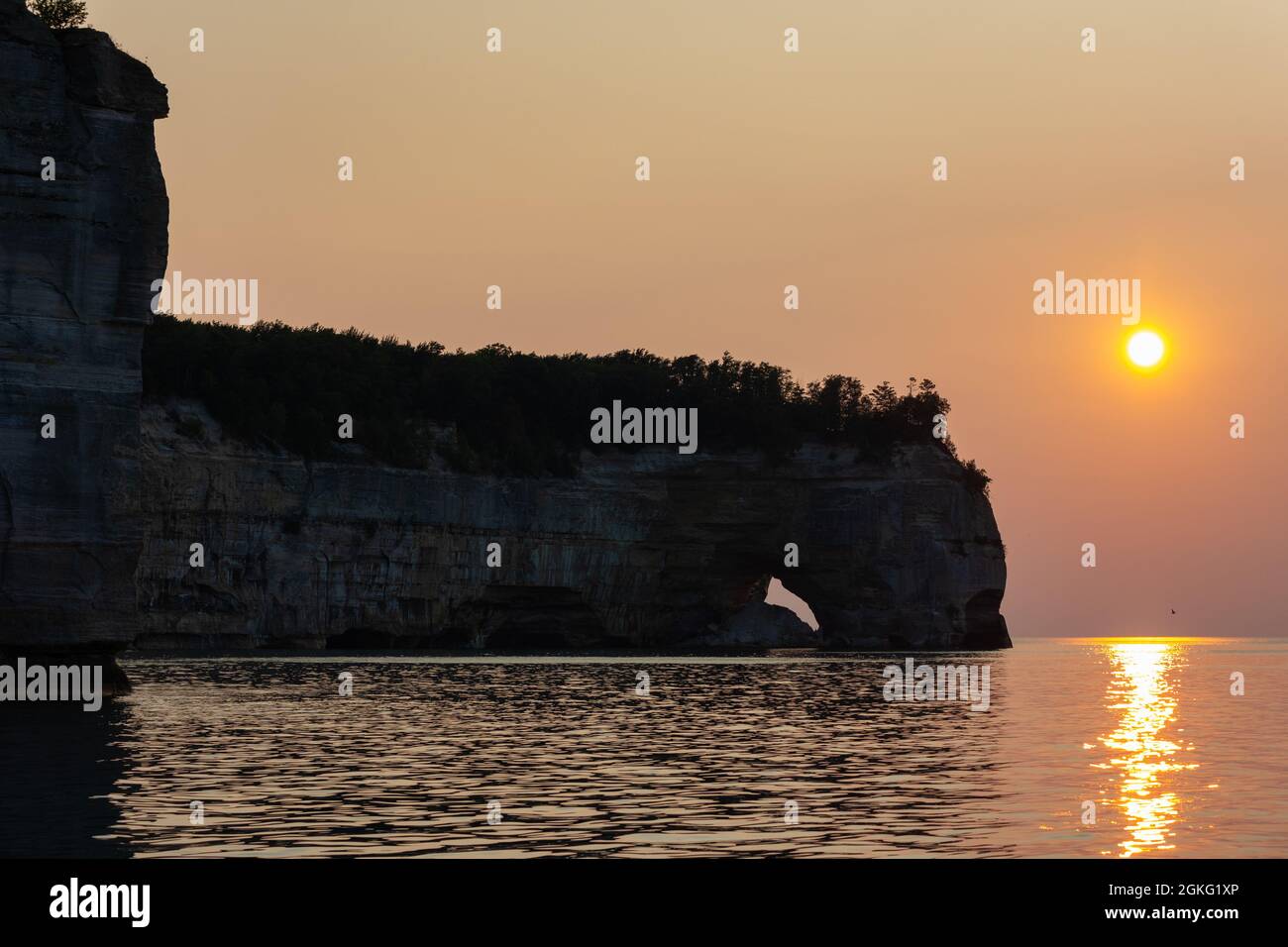 Sunset over a natural arch along Pictured Rocks National Lakeshore ...