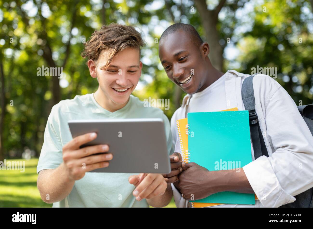 Student guy showing his project on digital tablet to friend, walking ...