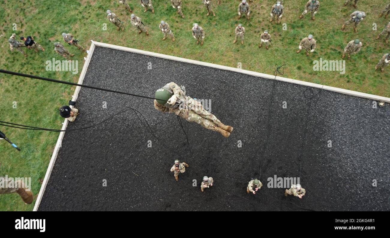Soldiers watch as one of their classmates descends the rappel tower ...
