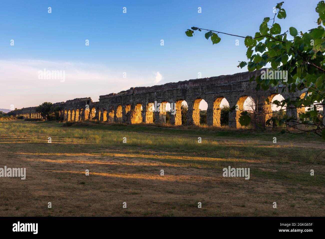 In the park of the ancient Roman aqueducts, the sun sets and the arches ...