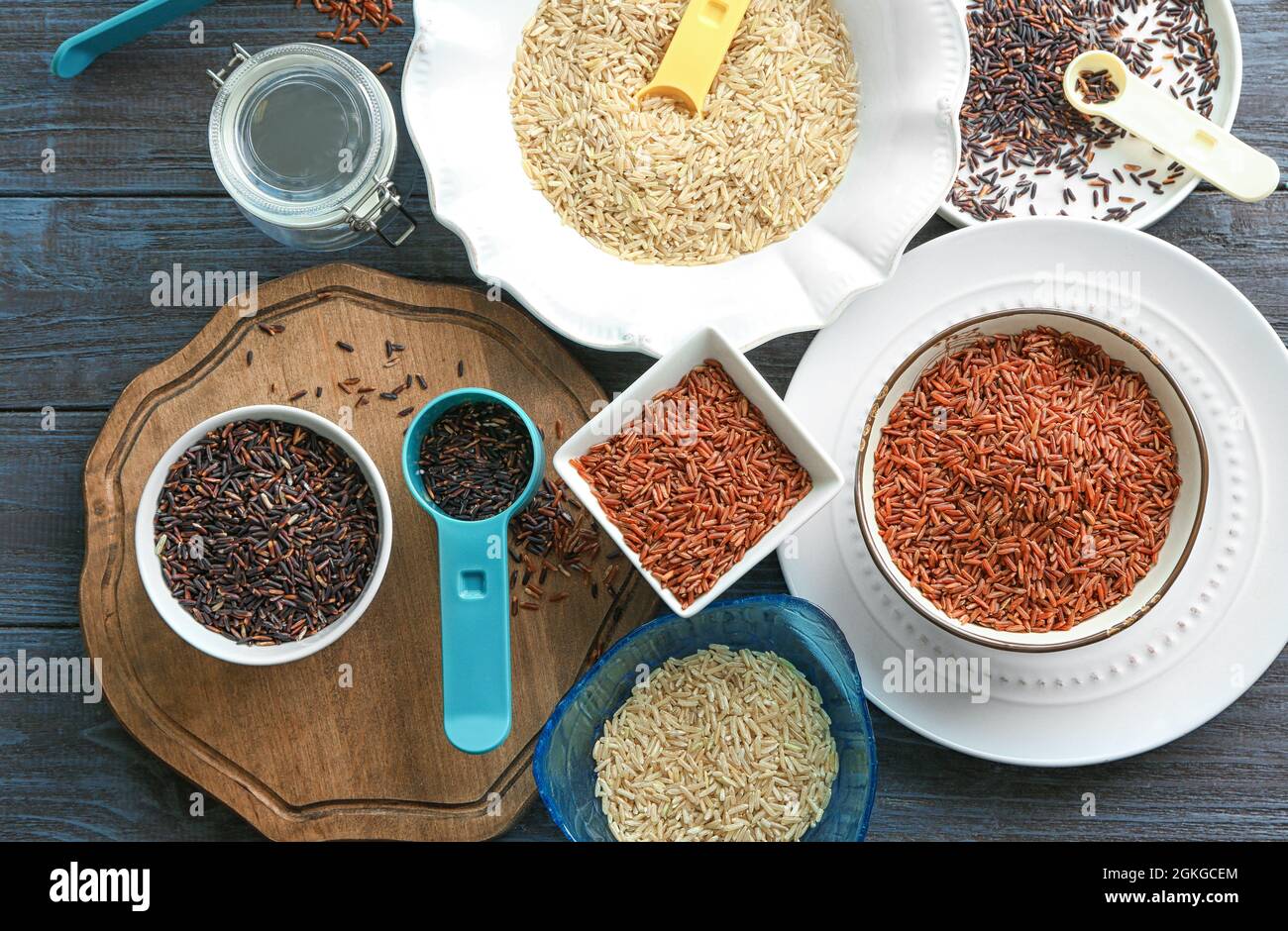 Different types of rice in bowls and plates on wooden table Stock Photo ...