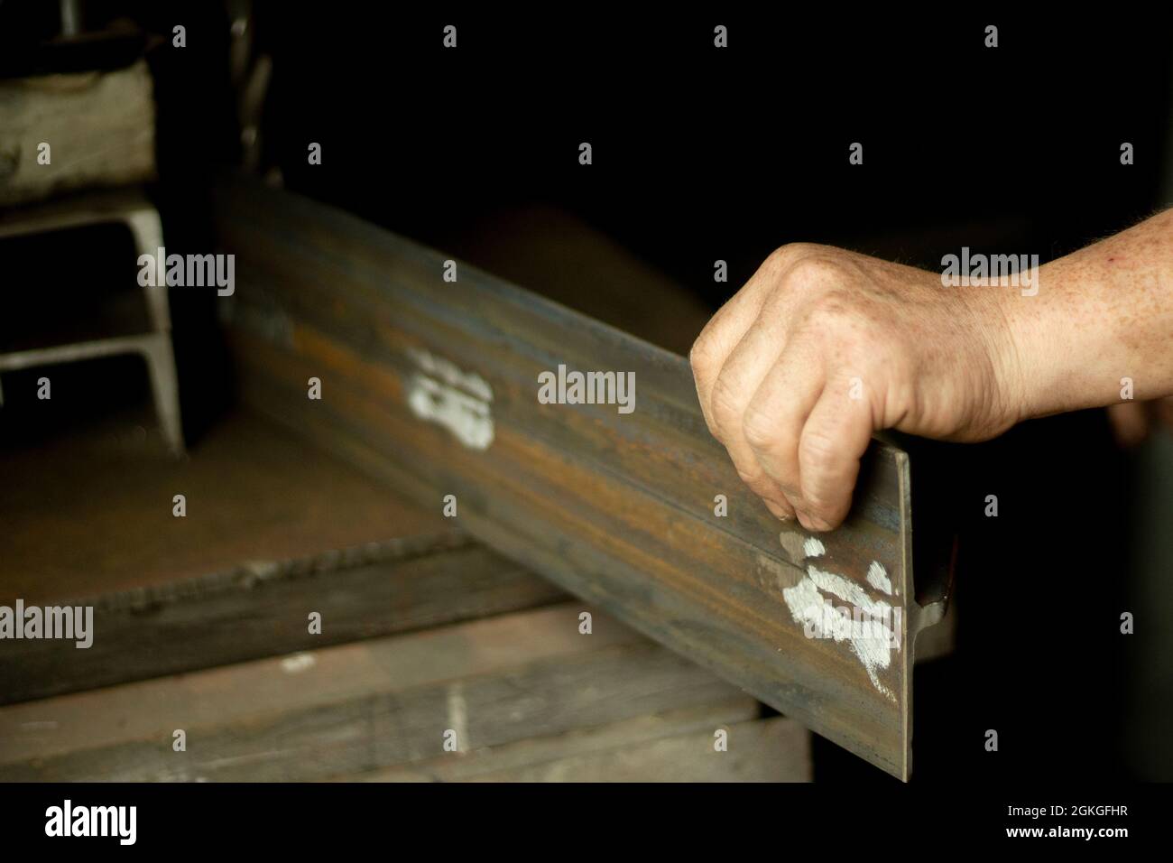 Worker with metal. The guy holds a steel part. Hard work in a ...