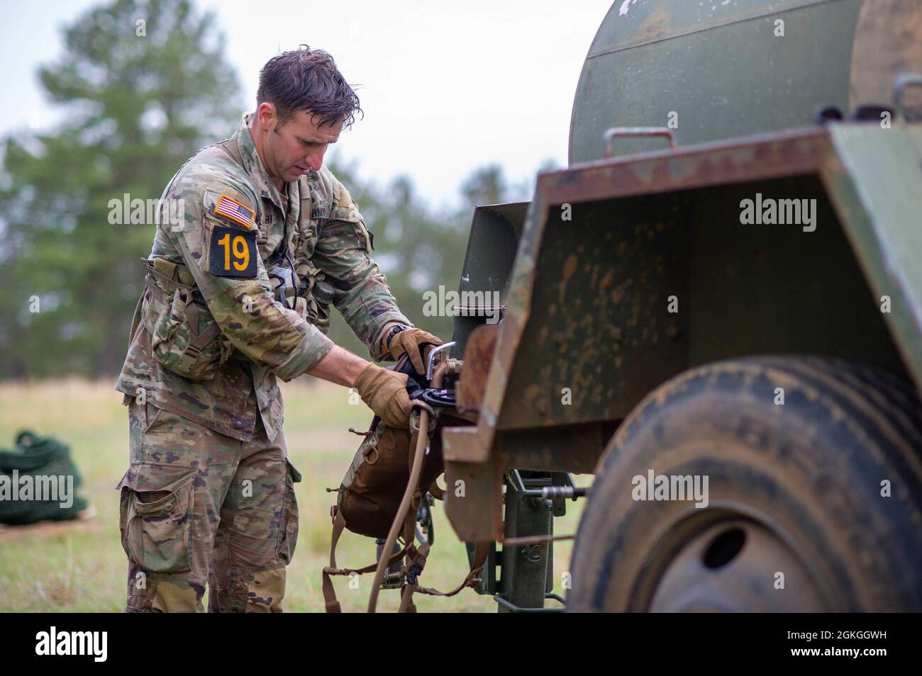 A member of Team 19 fills a water source while participating in the ...