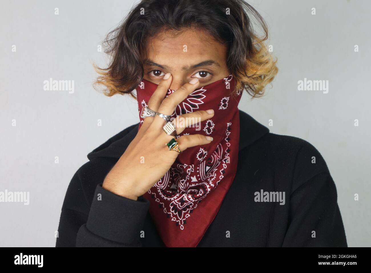 Young thug Indian male with a bandana covering his face and rings on ...