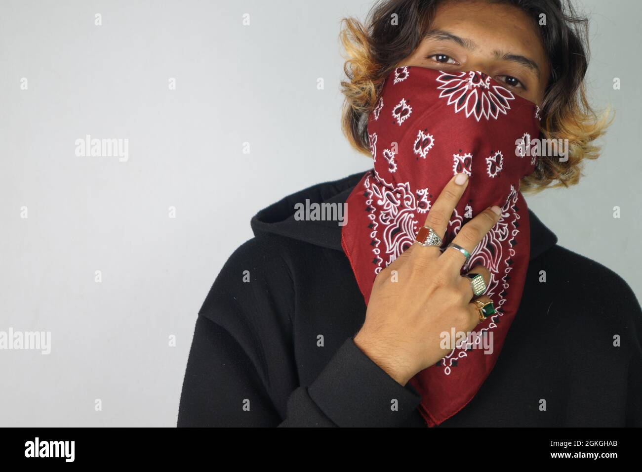 Young thug Indian male with a bandana covering his face and rings on ...