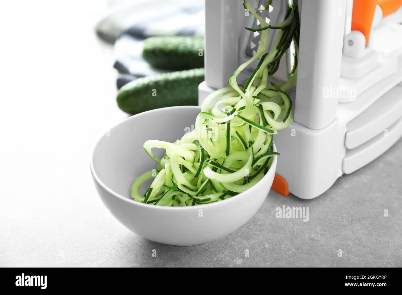 Spiral vegetable slicer with cucumber spaghetti on table Stock Photo ...