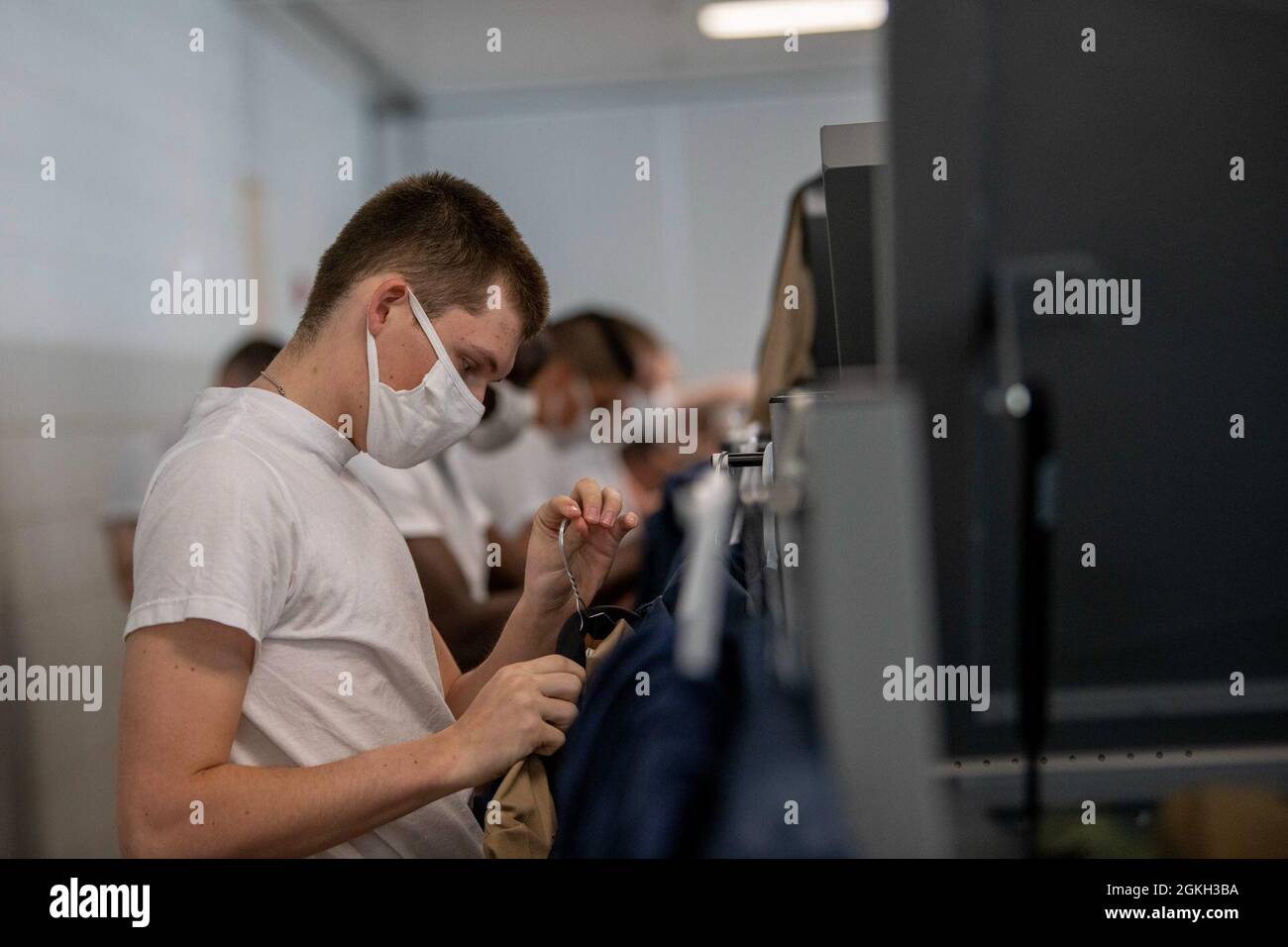 A recruit removes uniform items from his garment bag during a phase 3 ...