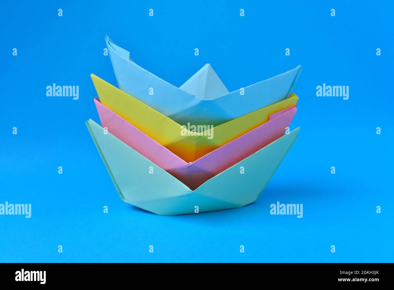 Colored paper boats on blue background Stock Photo - Alamy