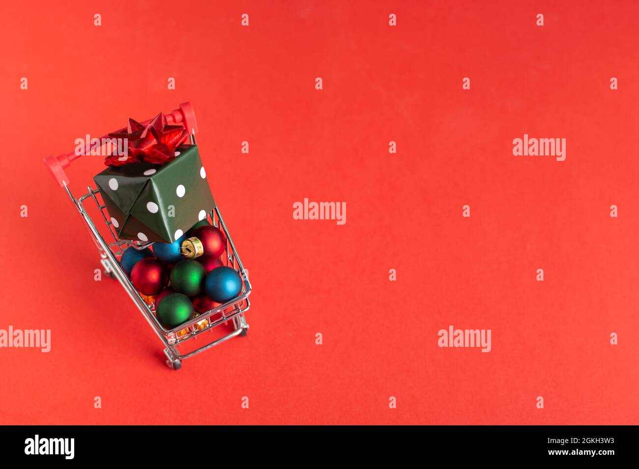 Shopping cart on wheels with Christmas ornaments and gift box on red ...
