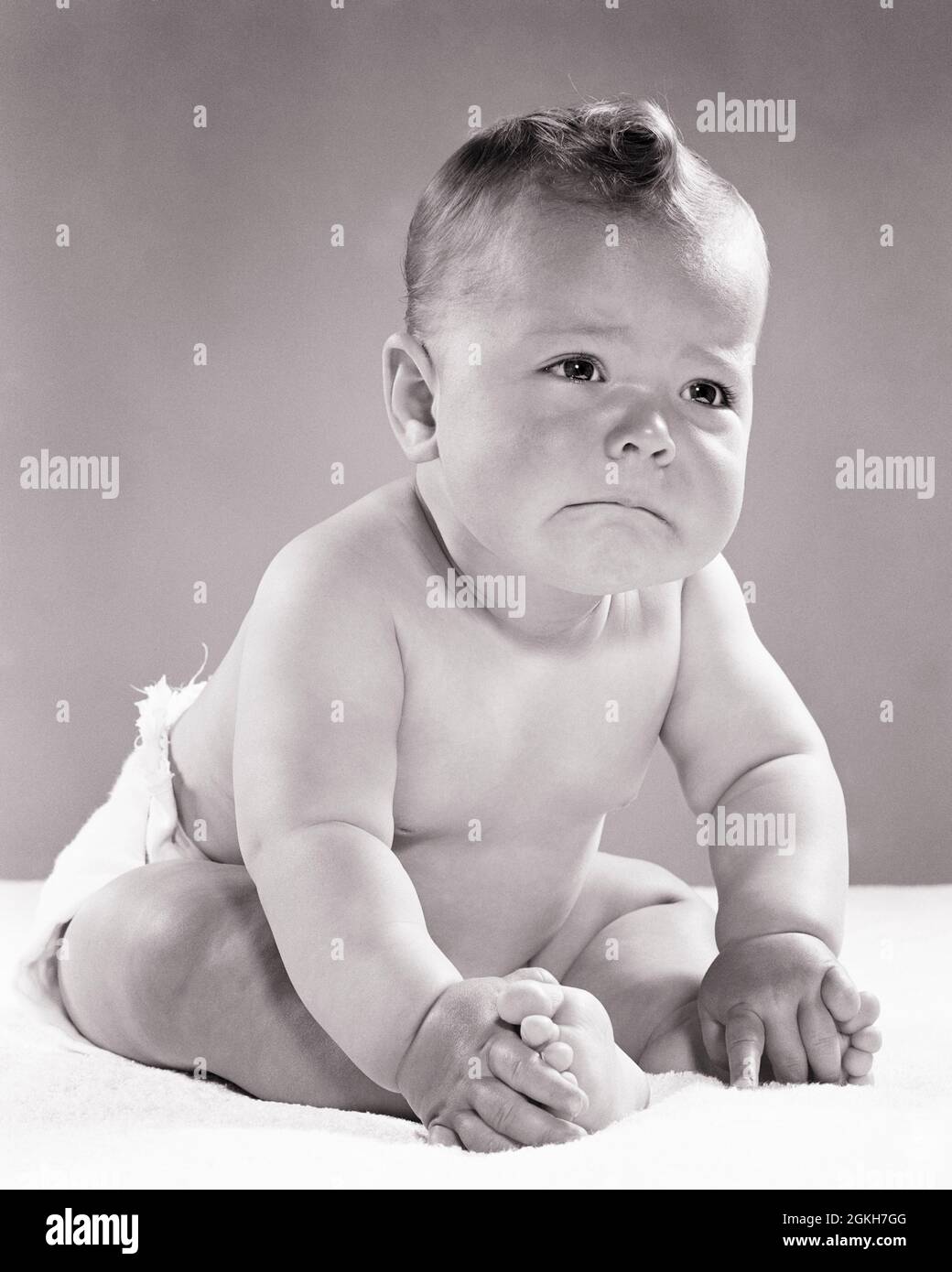1950s SAD DISGRUNTLED BABY SITTING LEANING FORWARD FINGERS HOLDING TOES ...