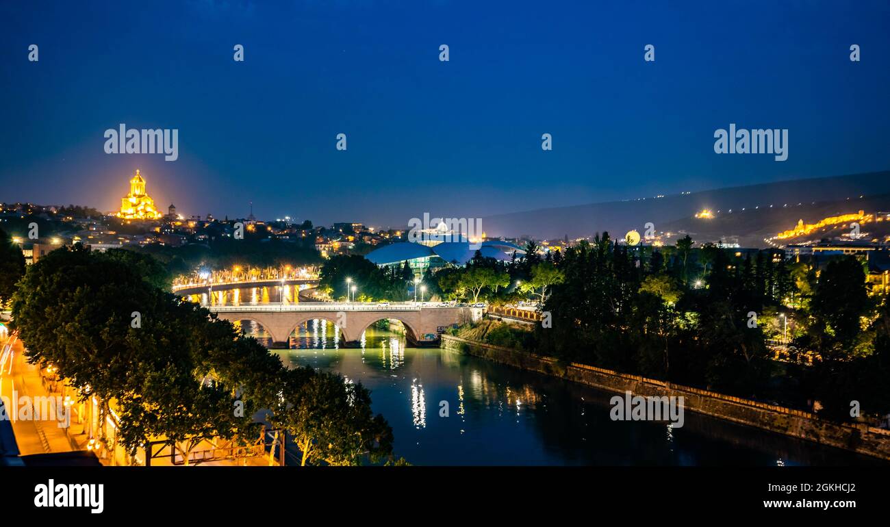 Scenic view of Mtkvari river and Holy Trinity Cathedral at night ...