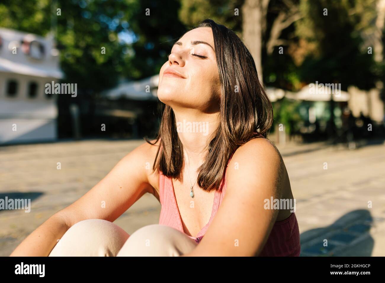 Young woman breathing deep fresh air and meditating while sitting on ...