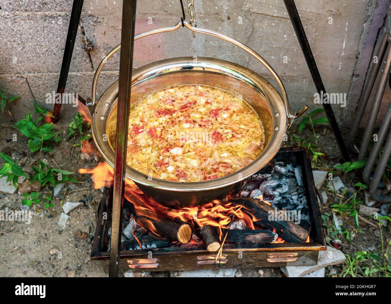 Pot with vegetables cauldron over open fire, preparing stew soup on ...