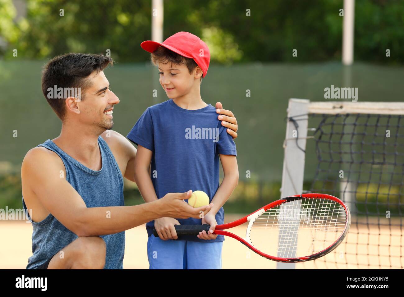 Young trainer with little boy on tennis court Stock Photo - Alamy