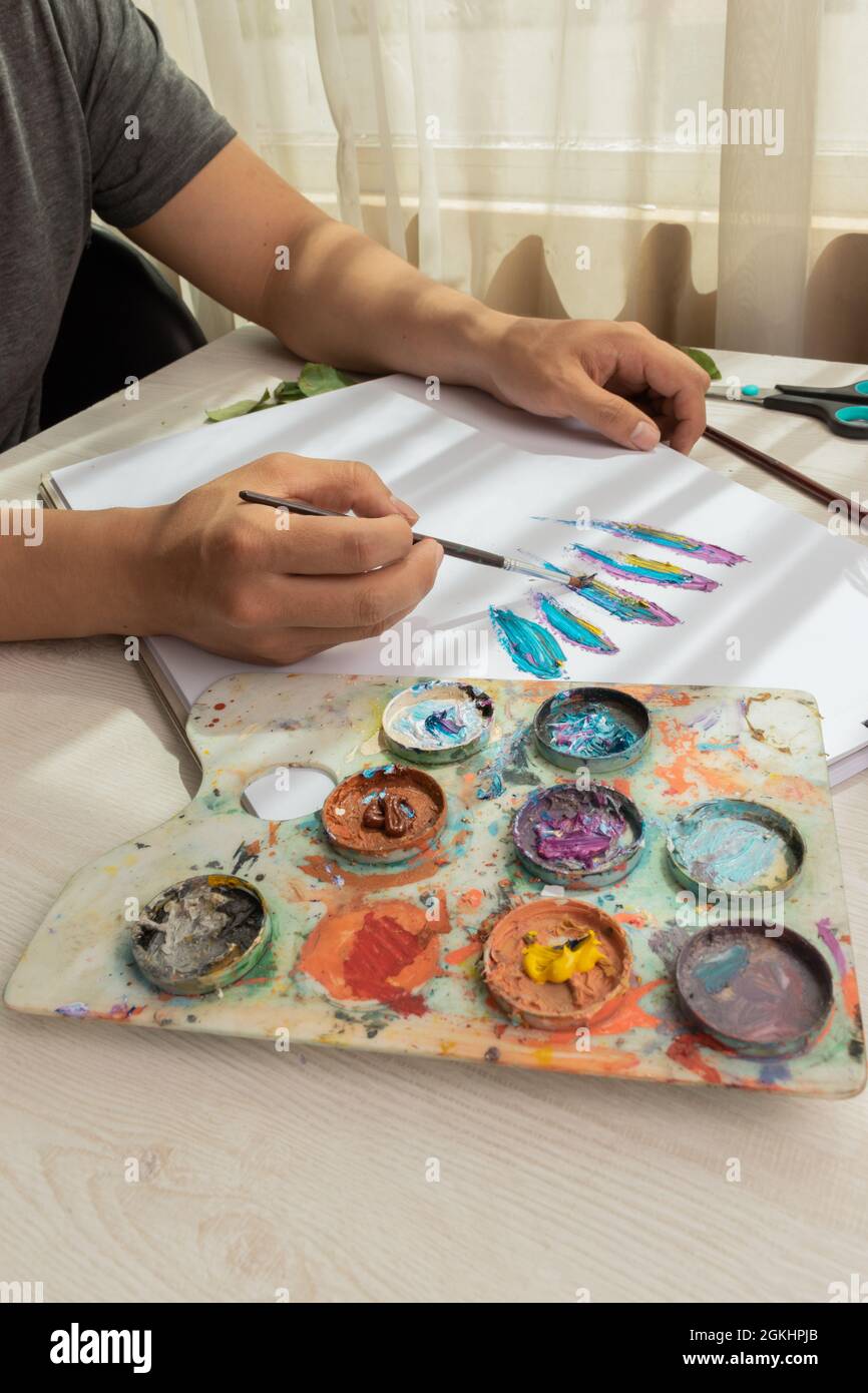 workplace, detail of an artist's hand painting with colors on a ...