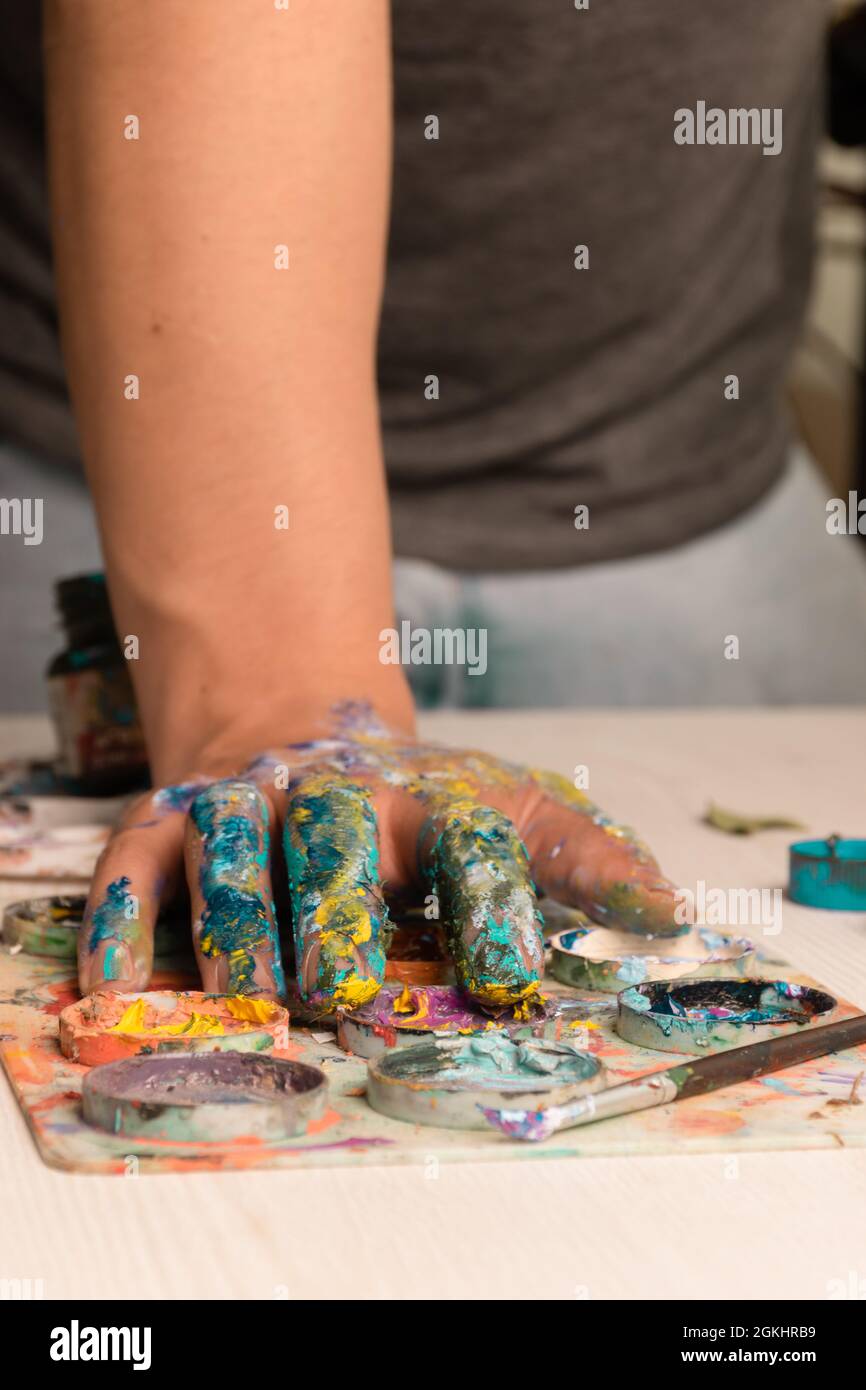 details of a person's hand stained with colors on a palette with paint ...