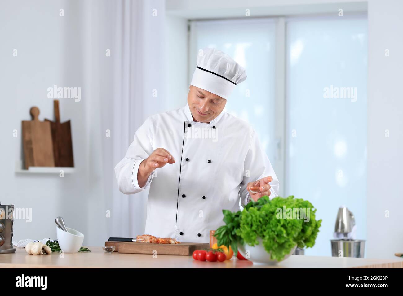 Male chef adding seasoning to meat in kitchen Stock Photo - Alamy