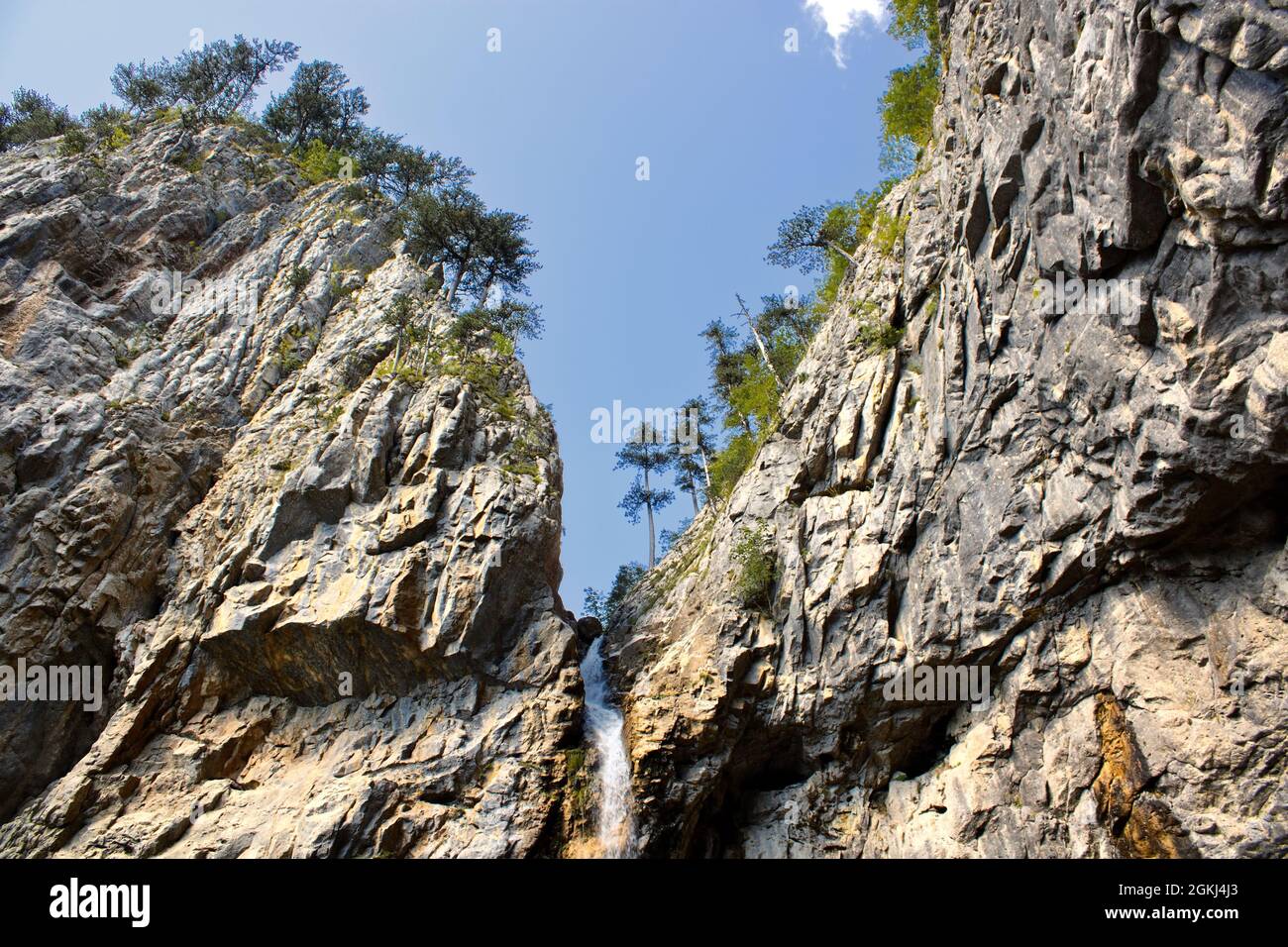 Gorgeous low angle shot of a waterfall running down a rocky cliff with ...