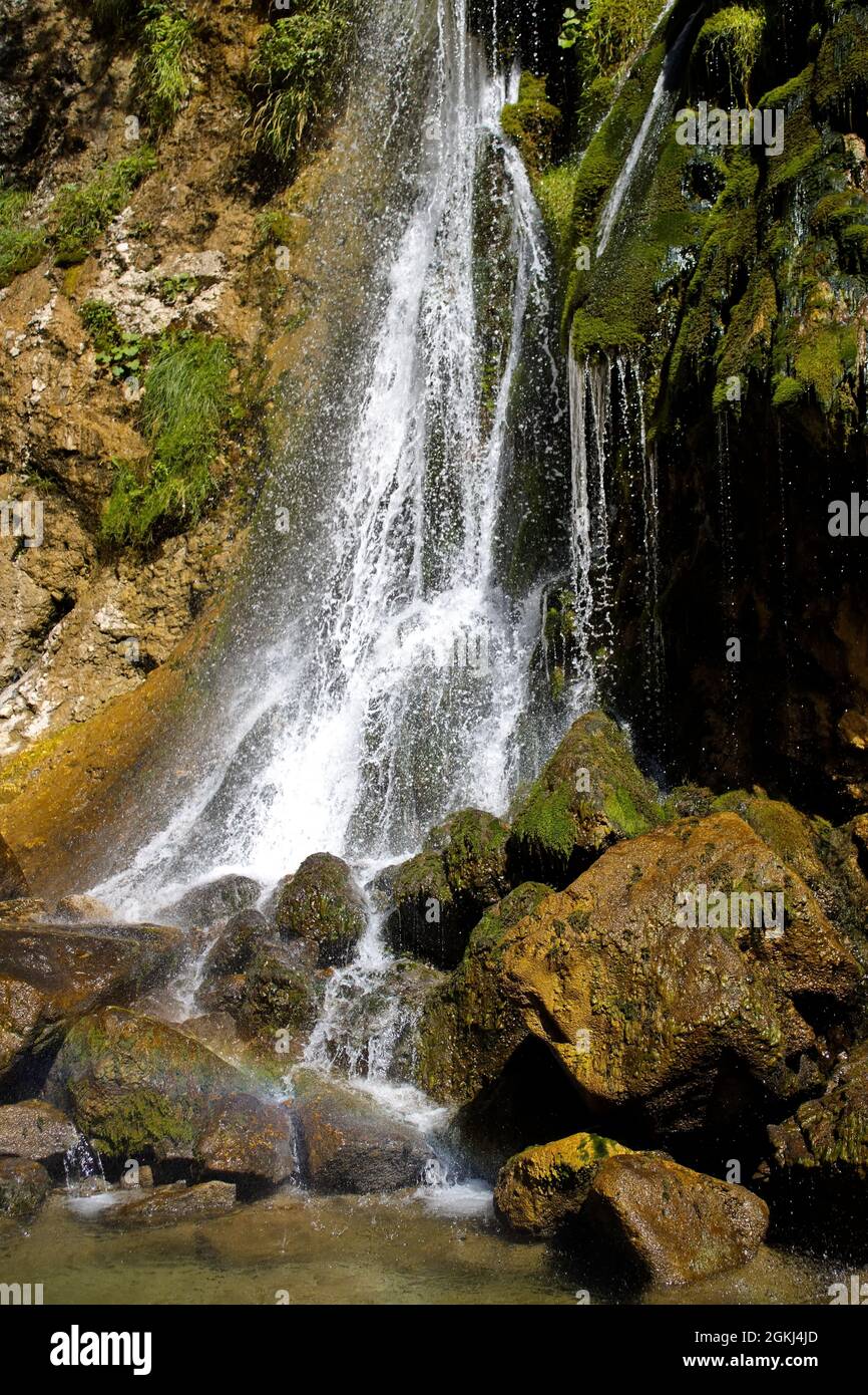 Vertical shot of a beautiful waterfall running down onto big mossy ...