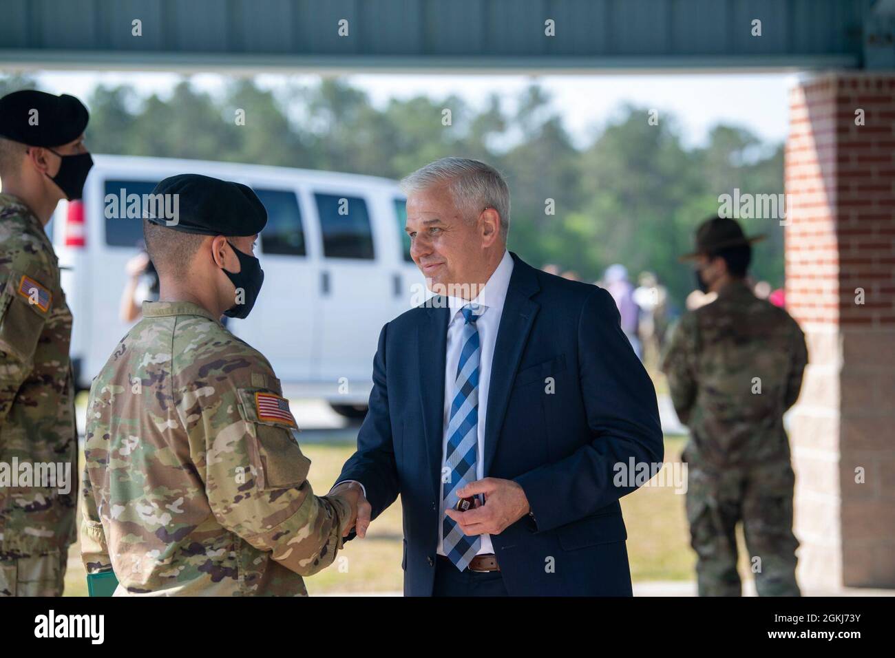 Acting under Secretary of the Army, Christopher Lowman gives a coin to ...