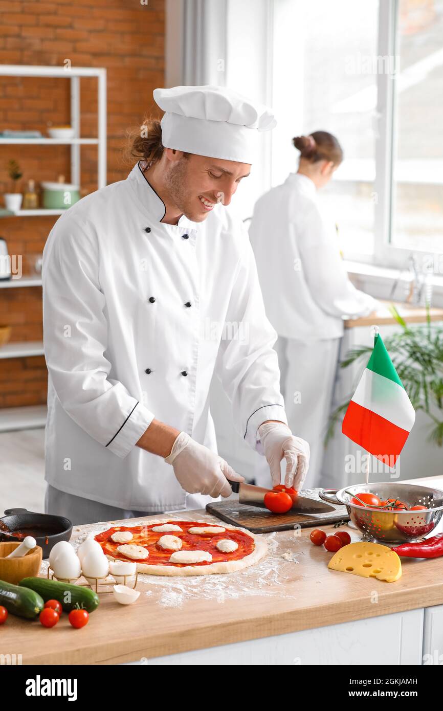 Italian chef cutting tomato in kitchen Stock Photo - Alamy