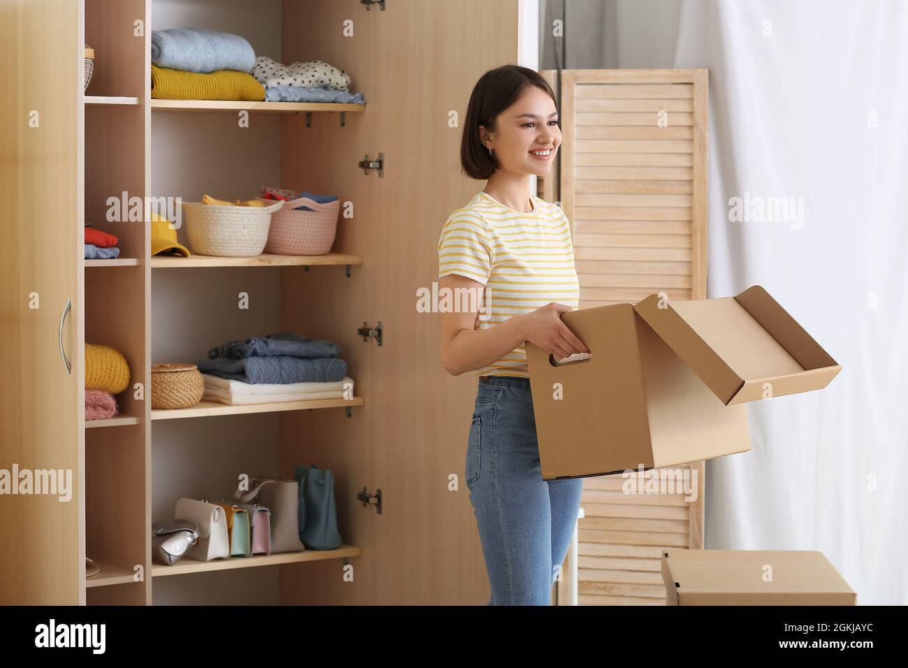 Young woman organizing clothes at wardrobe Stock Photo - Alamy