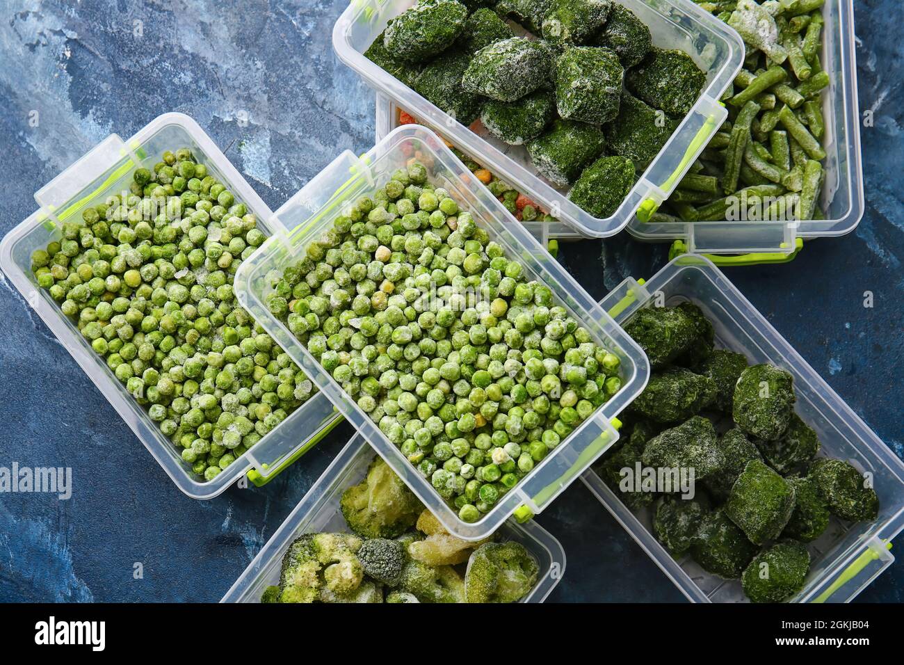 Plastic containers with different frozen vegetables on color background ...