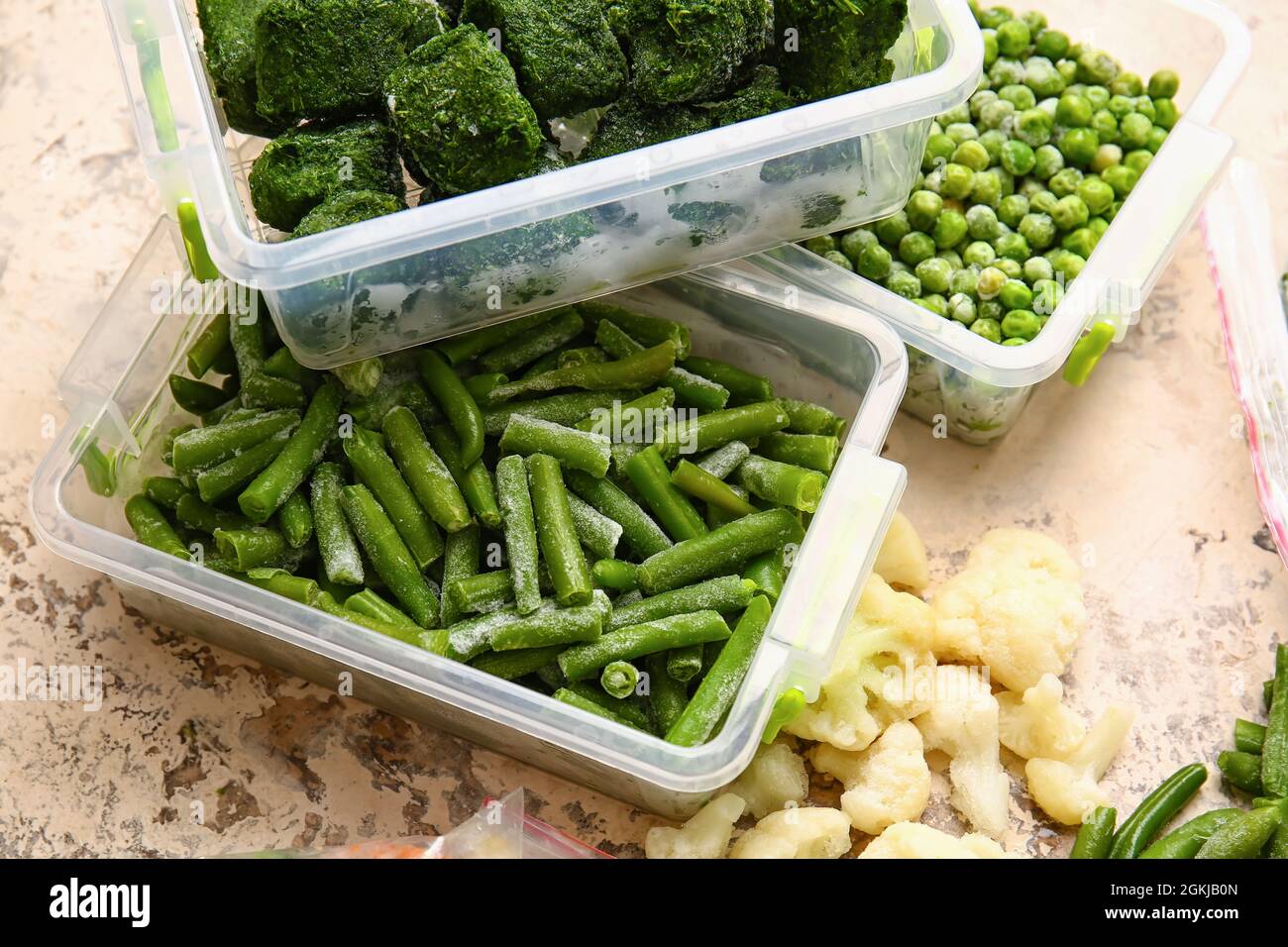 Plastic containers with different frozen vegetables on color background ...