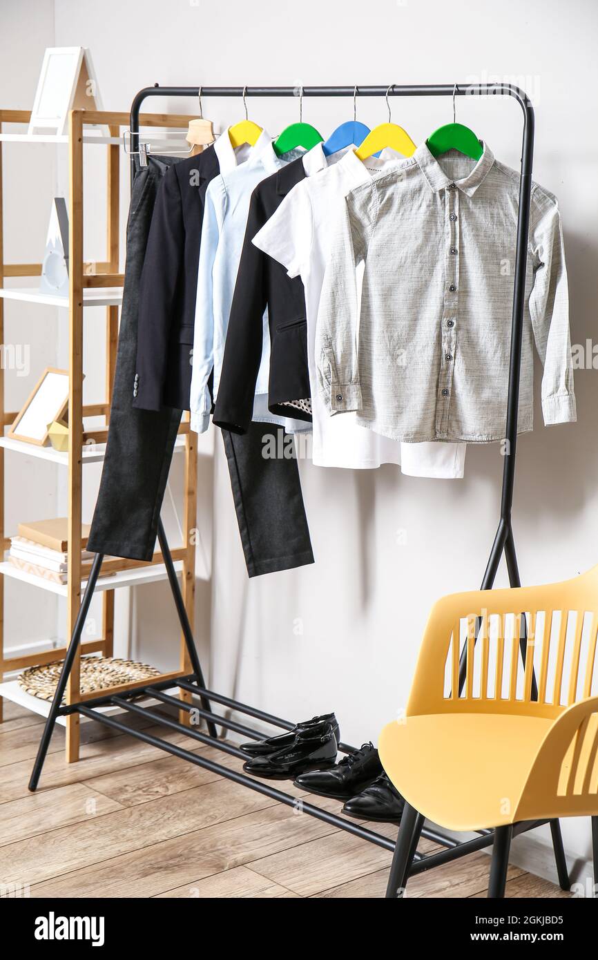 Rack with stylish school uniform near light wall Stock Photo - Alamy