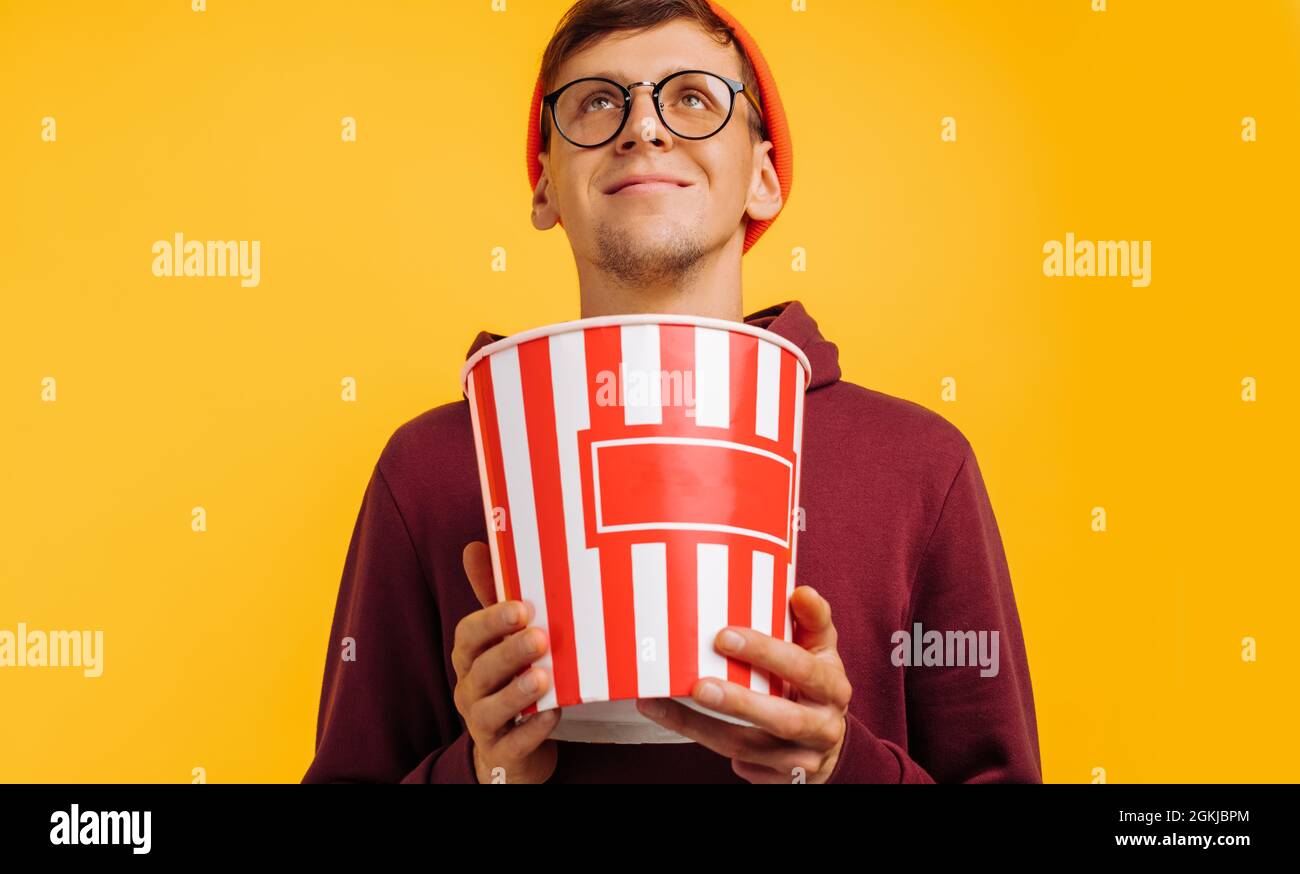 Photo of attractive crazy man holding big bucket of popcorn, eating ...