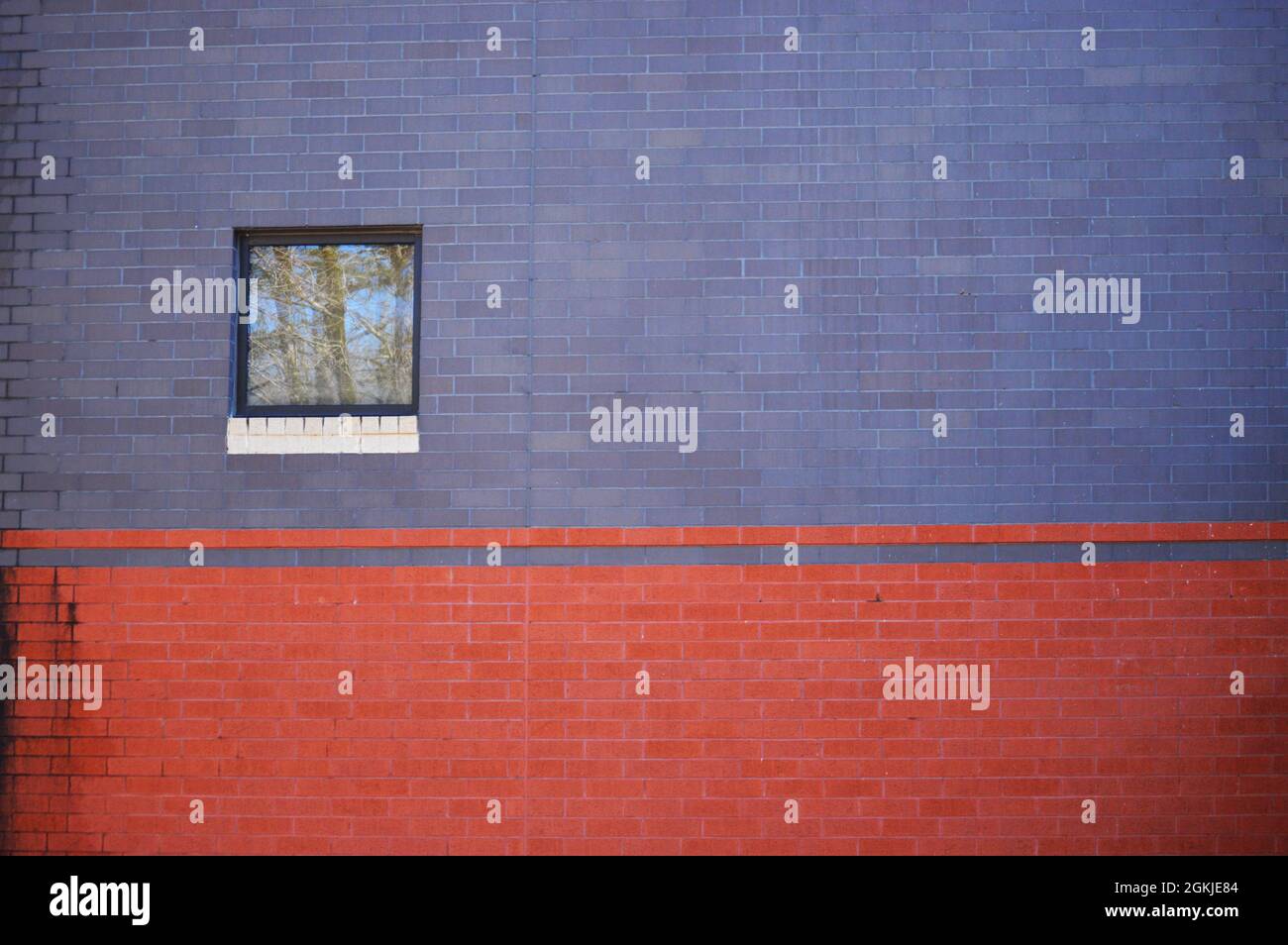A multi-colored brick wall with a reflective window Stock Photo - Alamy
