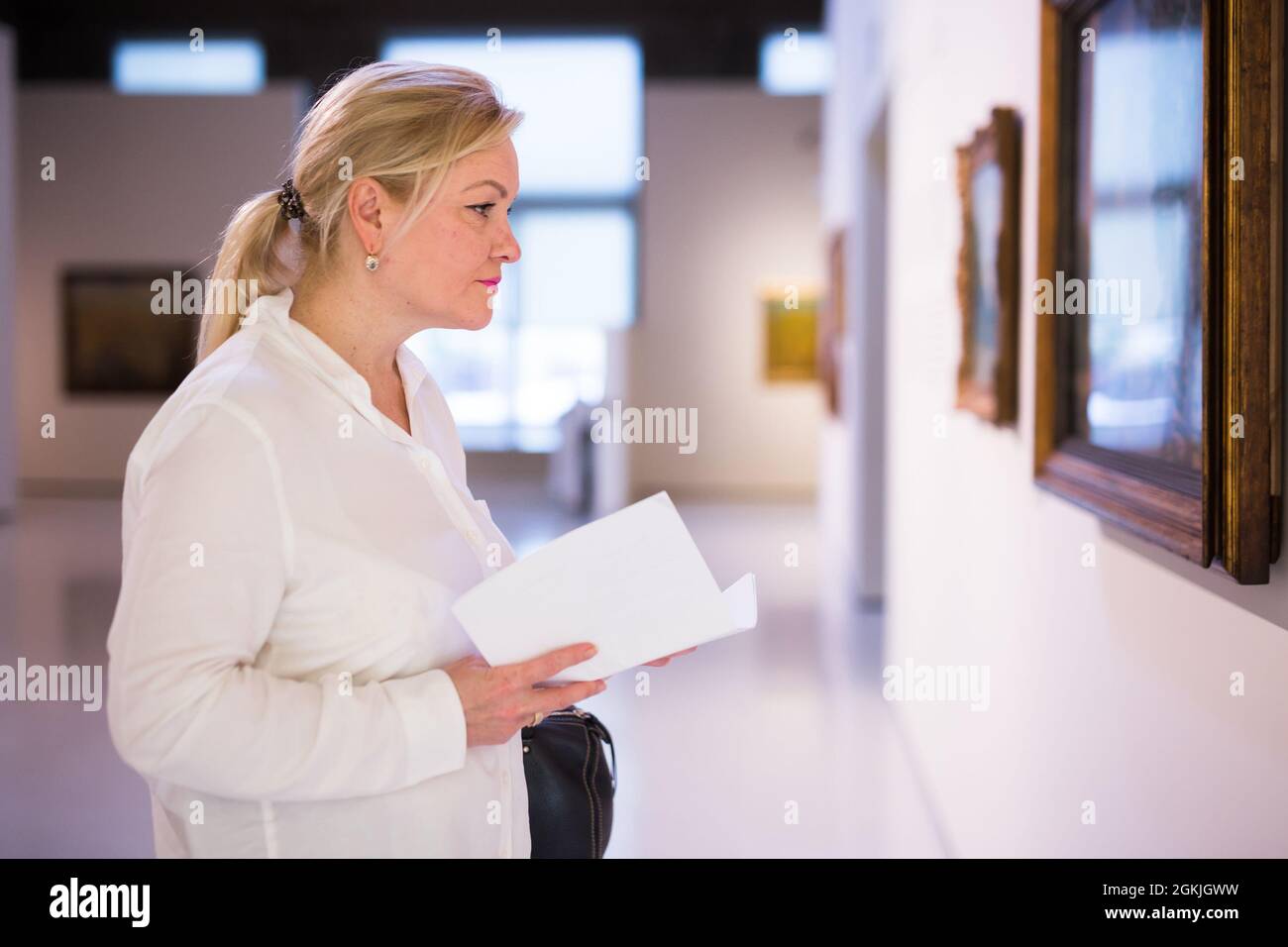 Senior female holding guidebook standing at exhibition Stock Photo - Alamy