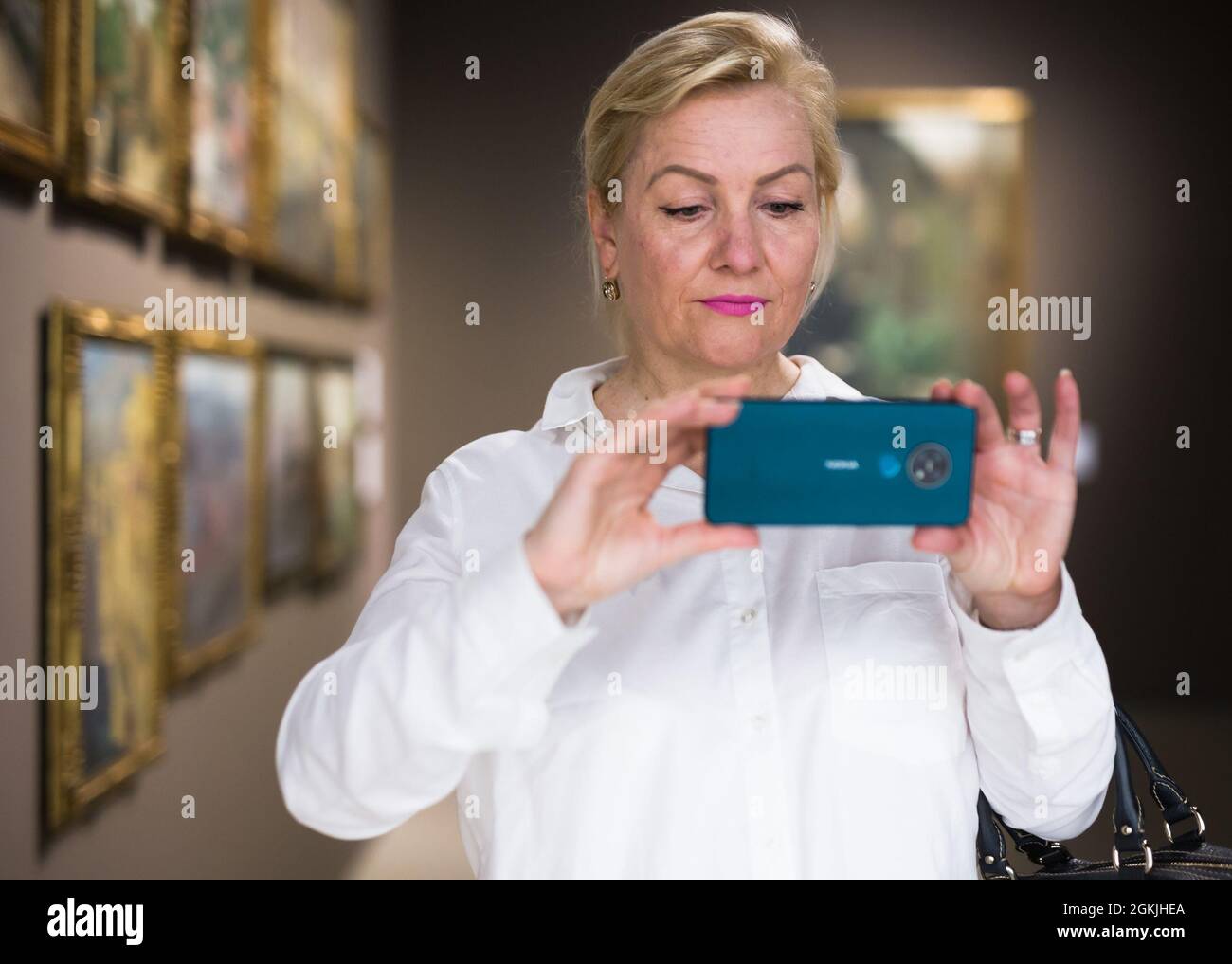 Female visitor taking picture in art gallery Stock Photo - Alamy