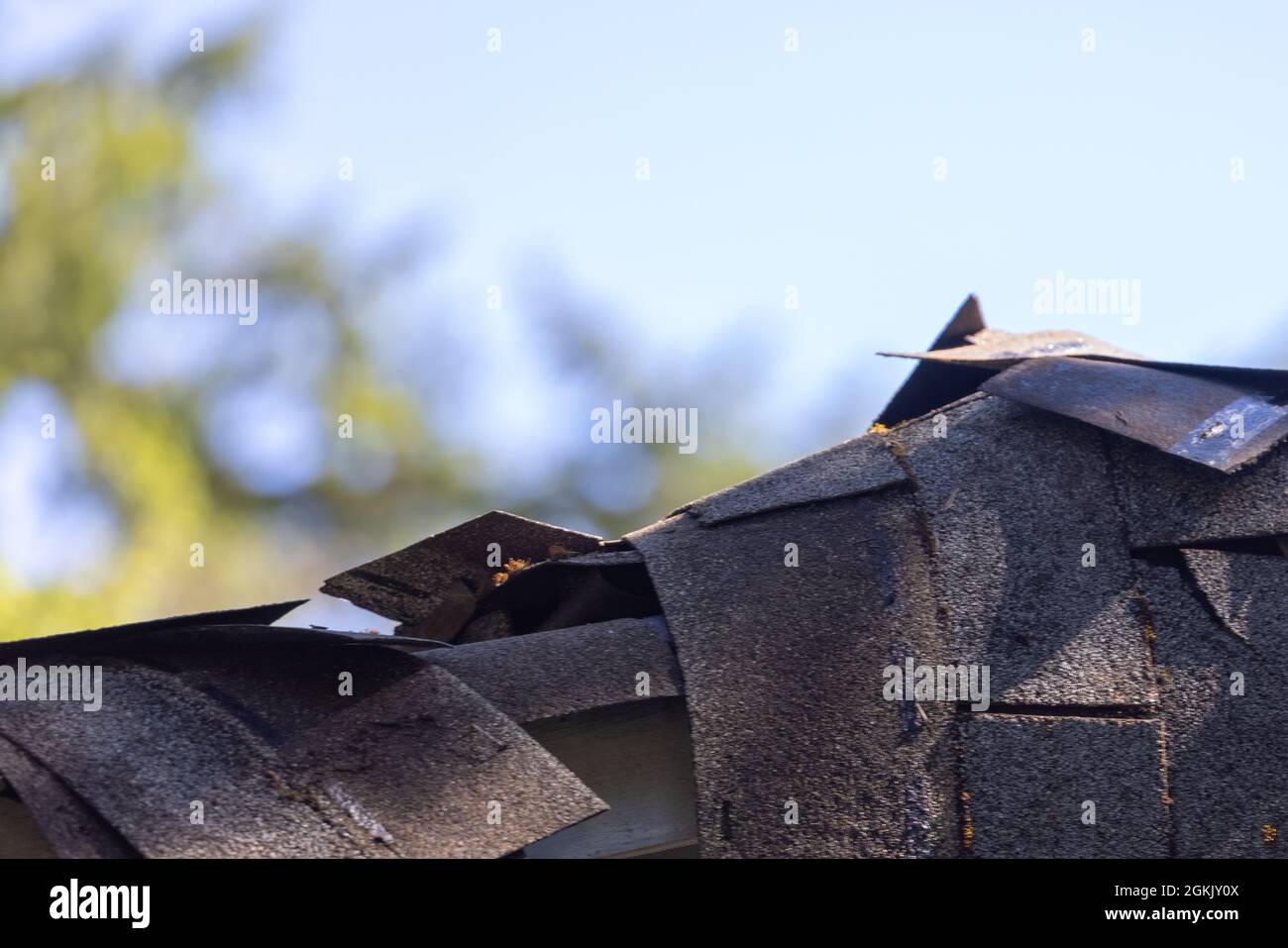 old damaged shingles piled up on the edge of a roof worn out and ready ...