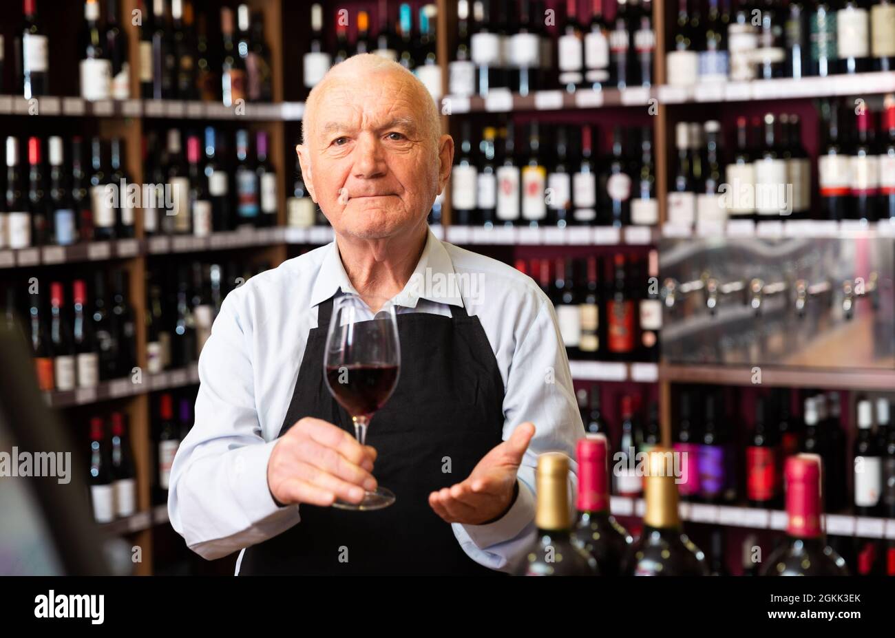 Successful elderly male owner of winery inviting to tasting wine of own ...