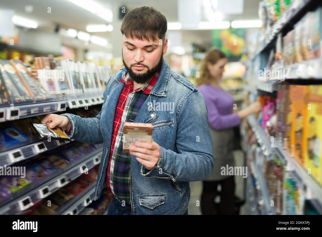 Positive bearded guy choosing chocolate Stock Photo - Alamy