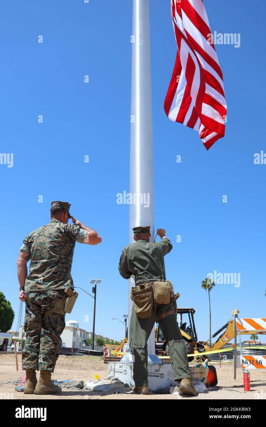 U.S. Marine Corps SSgt Aaron Seamons salutes as Cpl Eric Sanchez raises ...