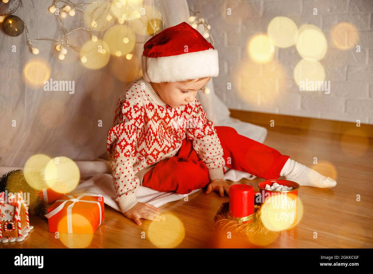 Curious boy peeks inside a Xmas present. Child kid with red gift box ...
