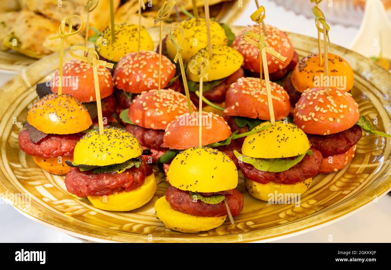 Mix of colorful mini burgers filled with fresh meat. Orange and yellow ...