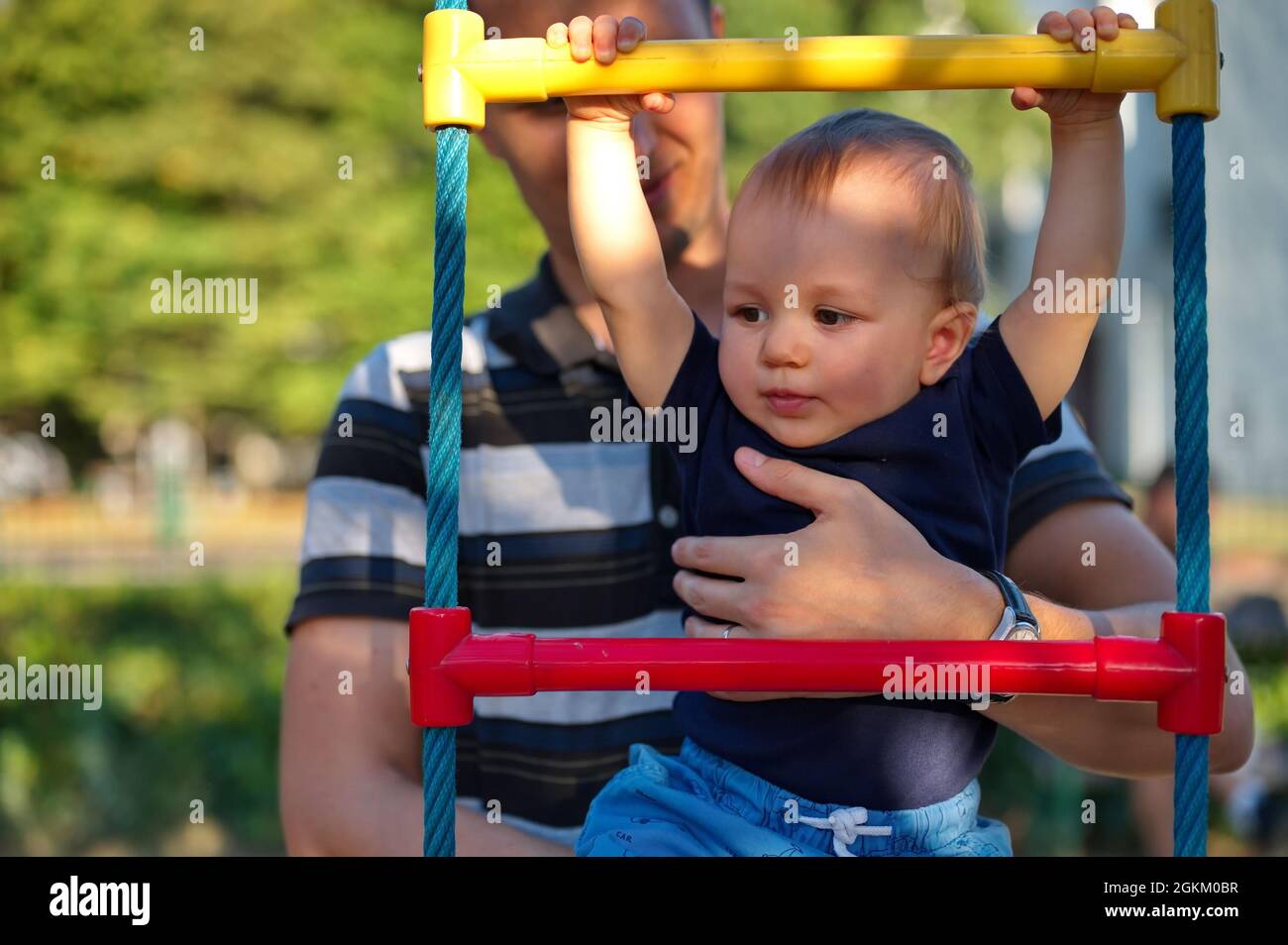 Father holding his little baby boy on playground ladder Stock Photo - Alamy