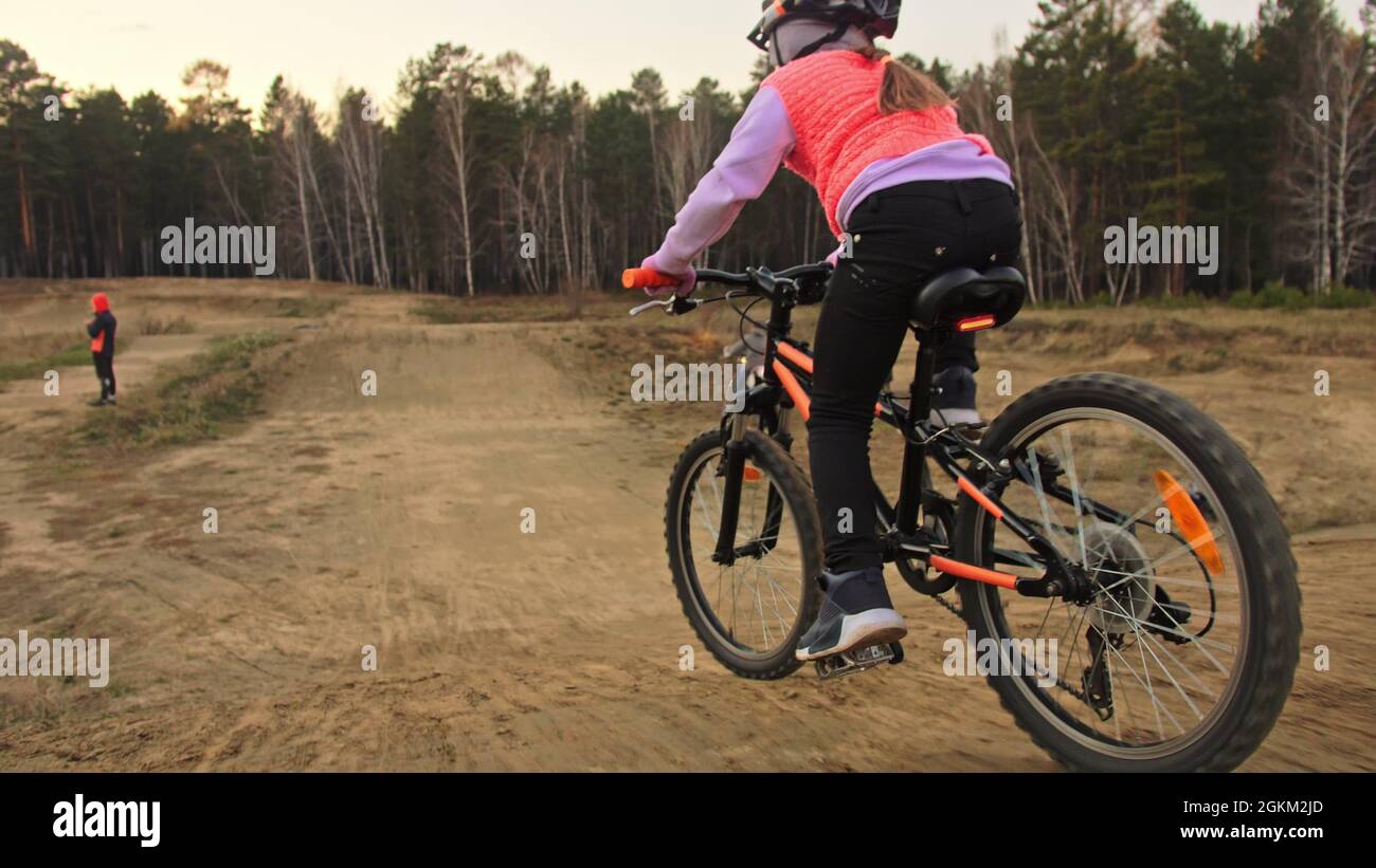 One caucasian children rides bike road track in dirt park. Girl riding ...