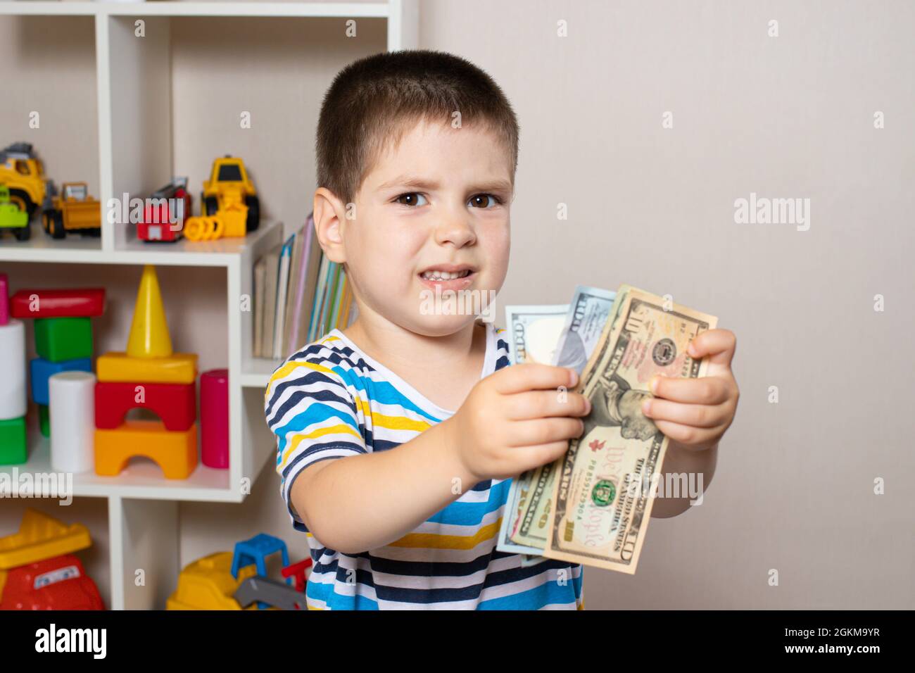 A little boy with a disgruntled expression keeps dollar bills Stock ...