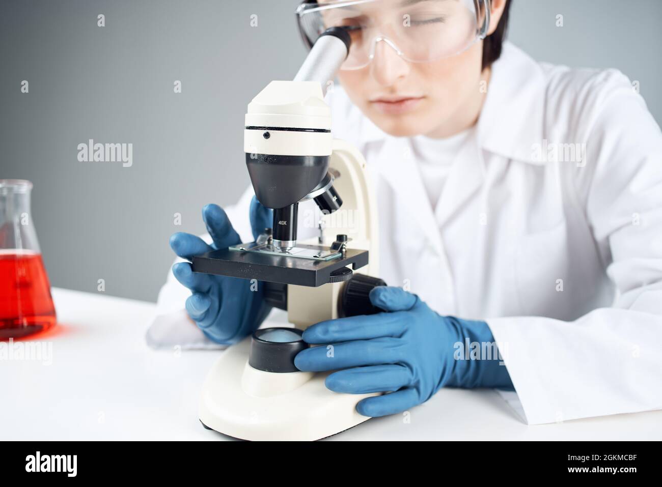 laboratory assistant looking through a microscope science research ...