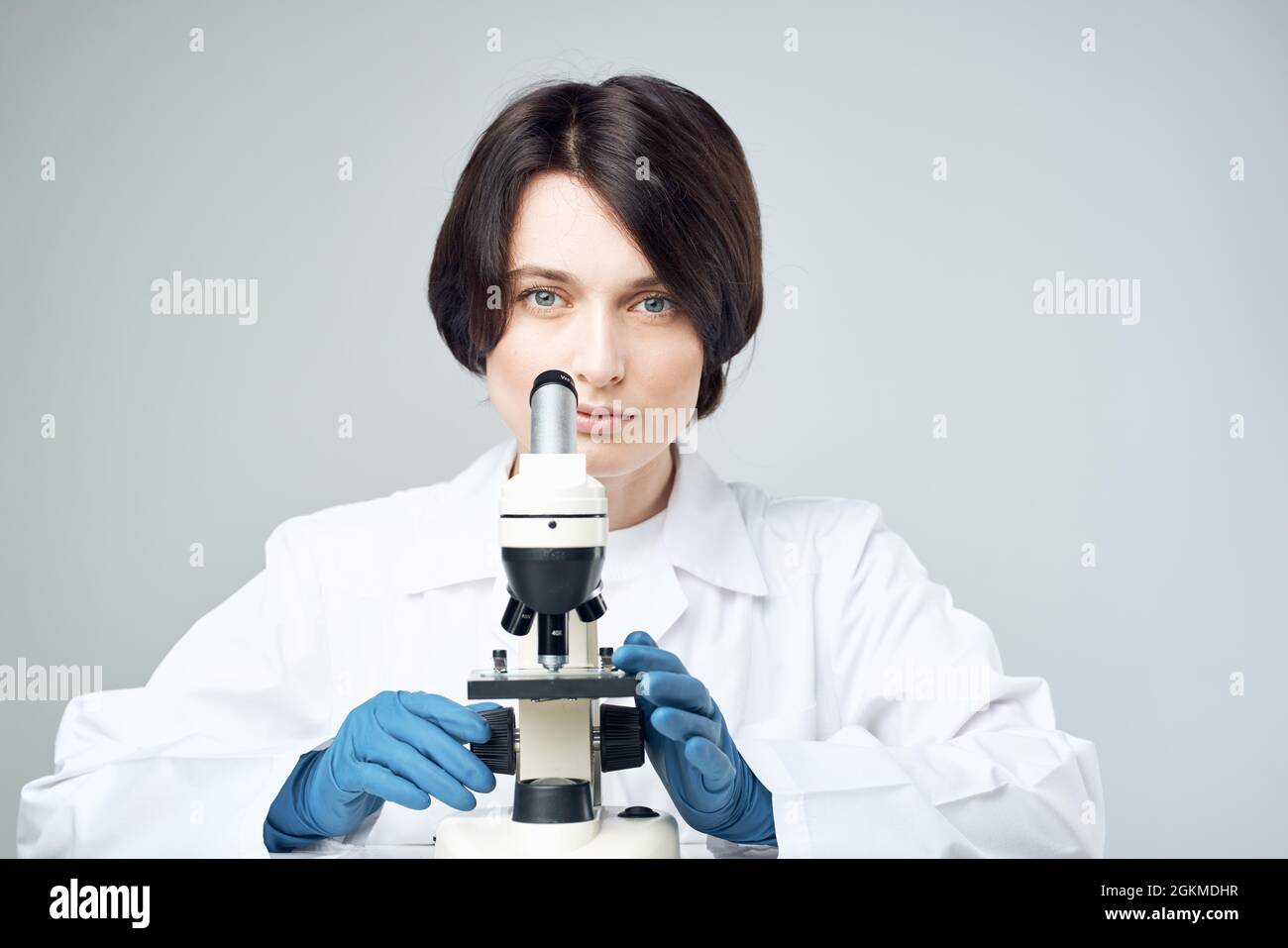 female laboratory assistant looking through a microscope diagnostics ...