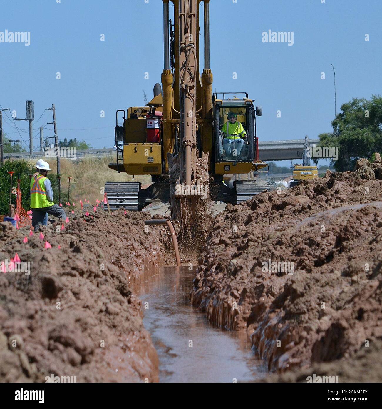 An excavator extracts a bucket full of mud during creation of a 35-foot ...