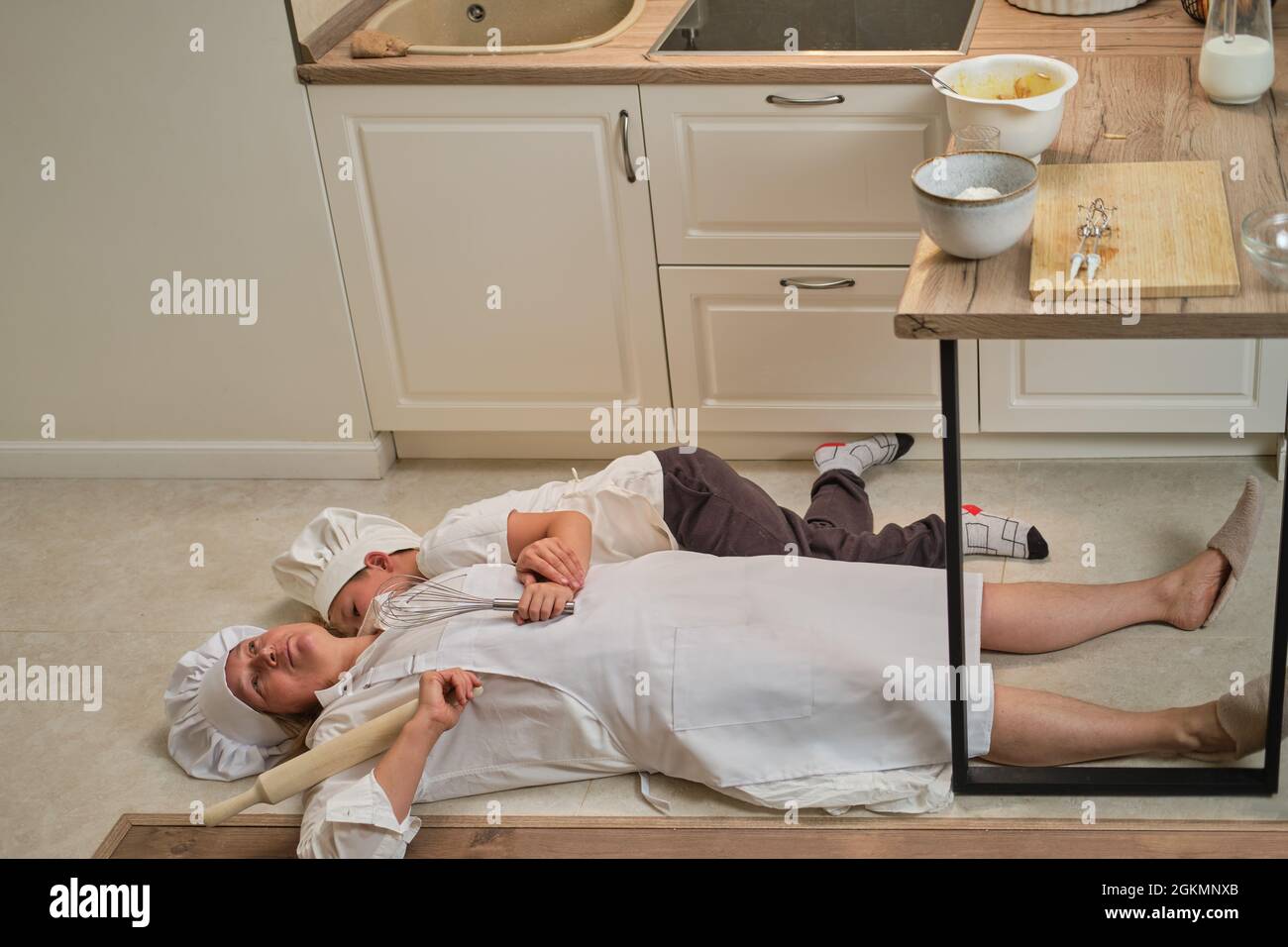 Funny mom and son relax in the kitchen after cooking. A tired woman and ...